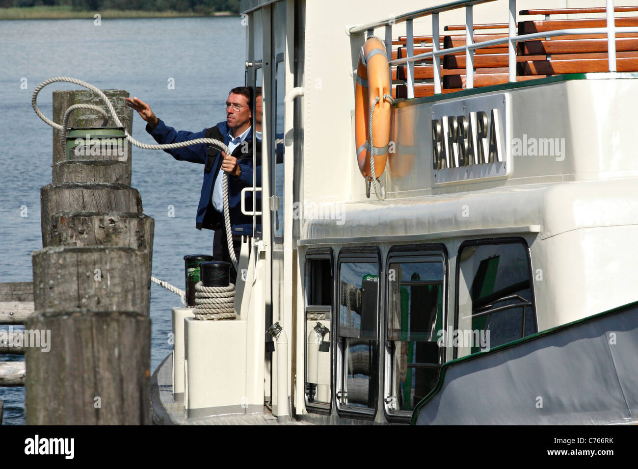 Crewman throwing a rope over a pylon from a Chiemsee ferry, Prien Stock ...