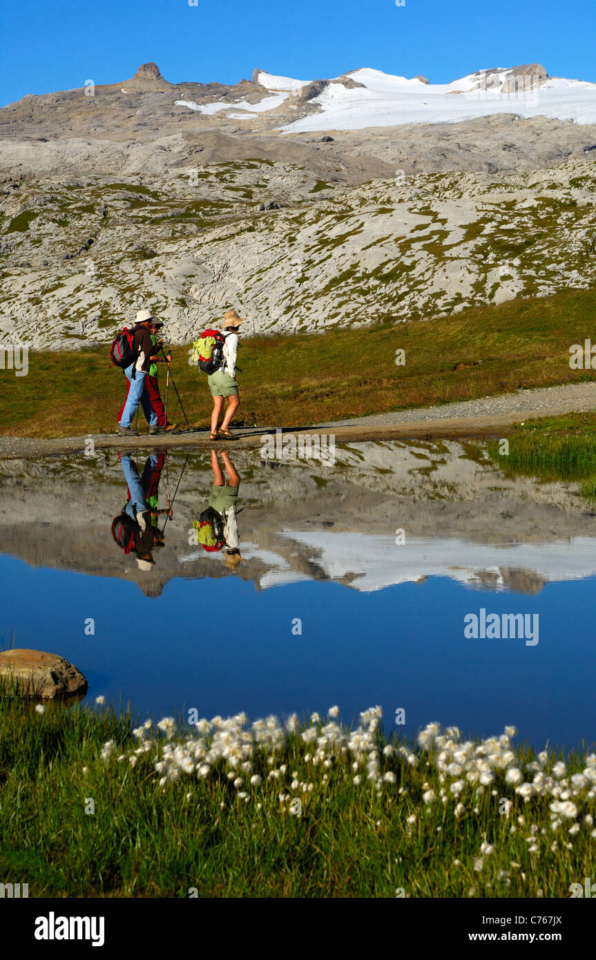 Hikers passing by a small mountain lake at the Sanetsch pass on the way ...
