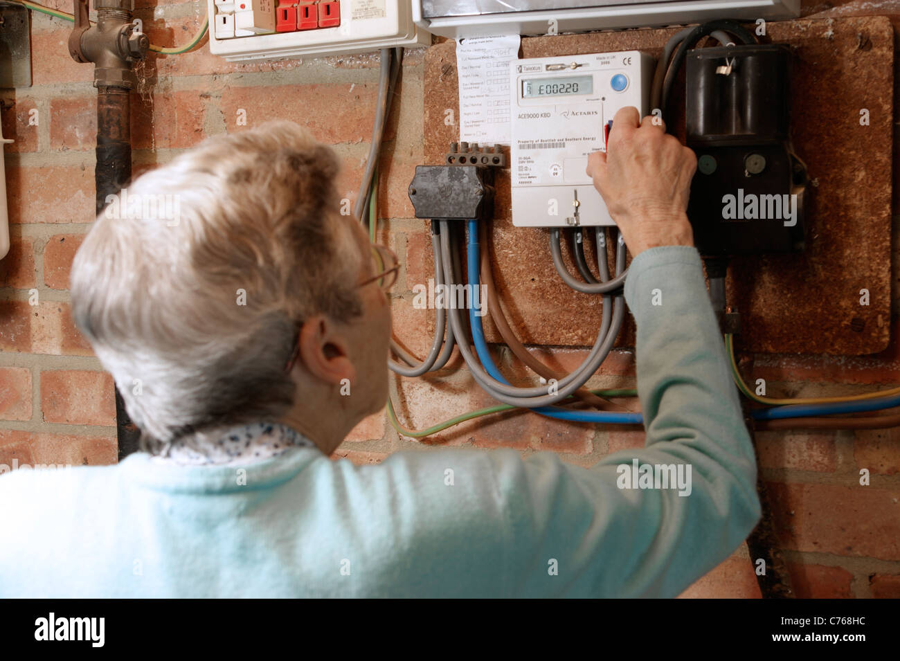 elderly woman using a quantum key prepayment electric meter & checking ...