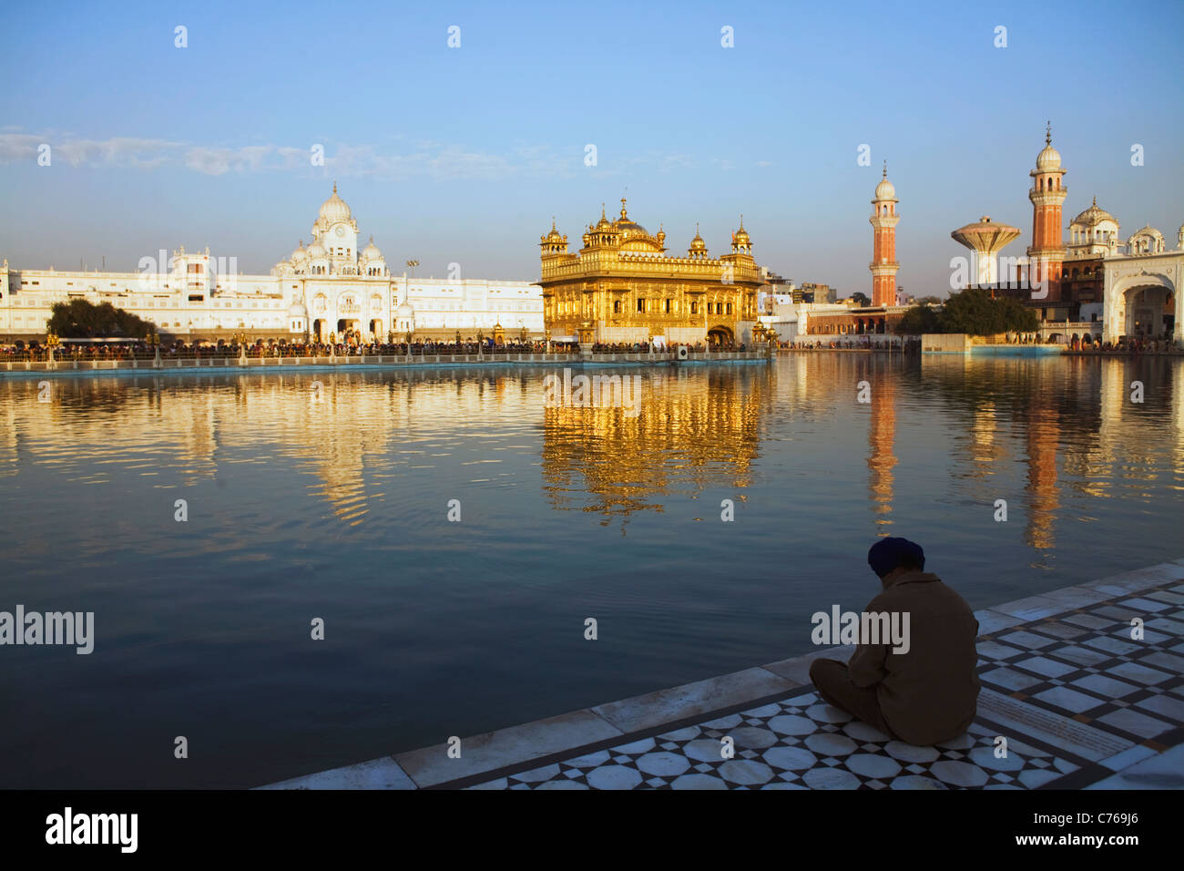 A man sits by the lake which surrounds the holy Sikh Golden Temple in ...