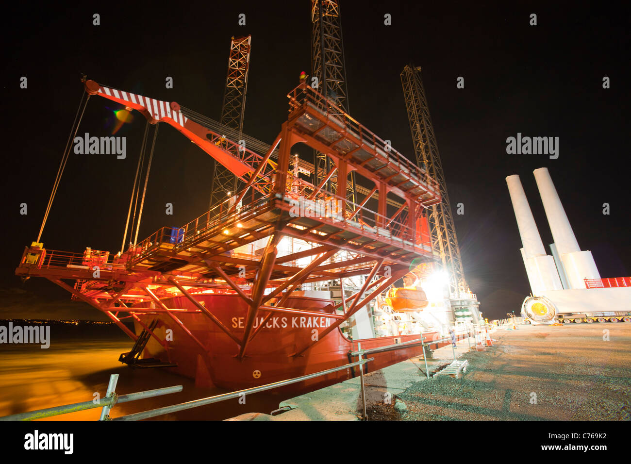 A jack up barge being loaded with wind turbine parts at night, for the ...