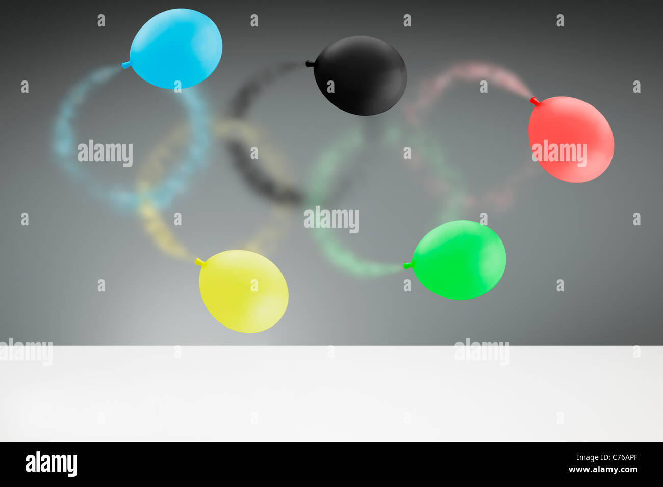 Olympic coloured party balloons swirling around to make olympics rings ...