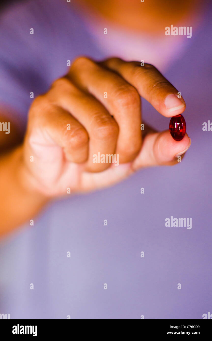 holding a capsule, a red tablet is handed out by a woman Stock Photo ...
