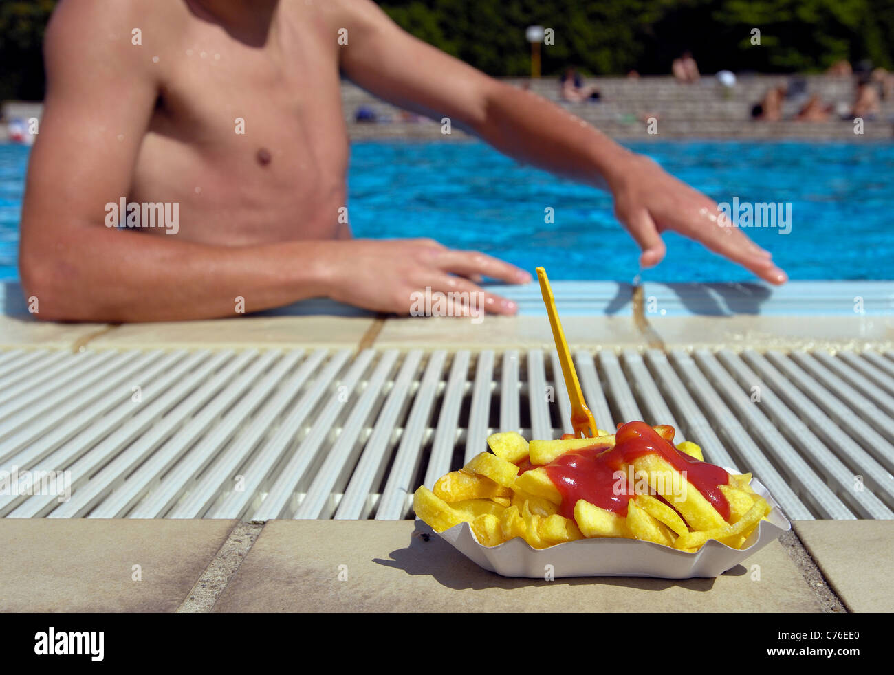 A bather in a swimming pool reaching for French fries Stock Photo - Alamy