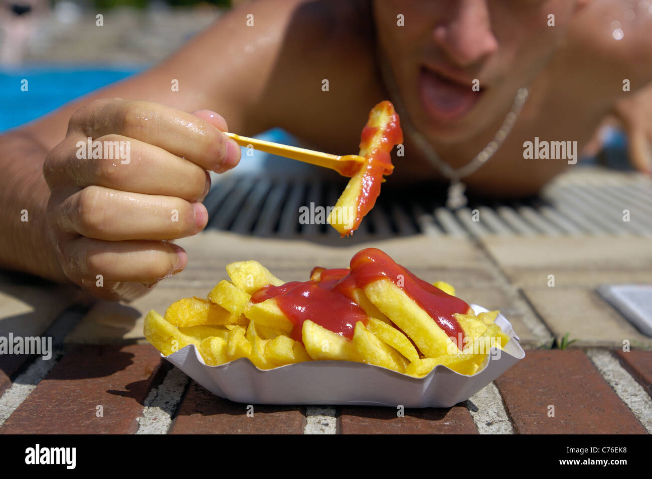 A bather in a swimming pool reaching for French fries Stock Photo - Alamy