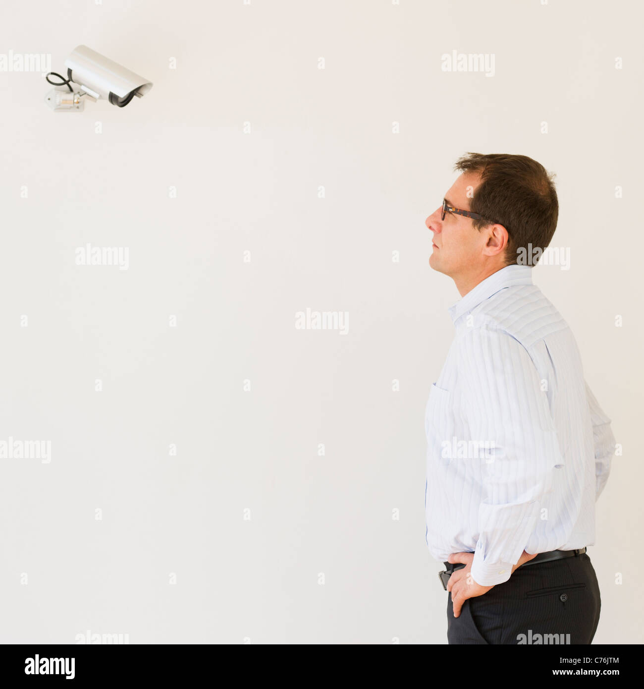 Businessman under surveillance of security camera Stock Photo - Alamy
