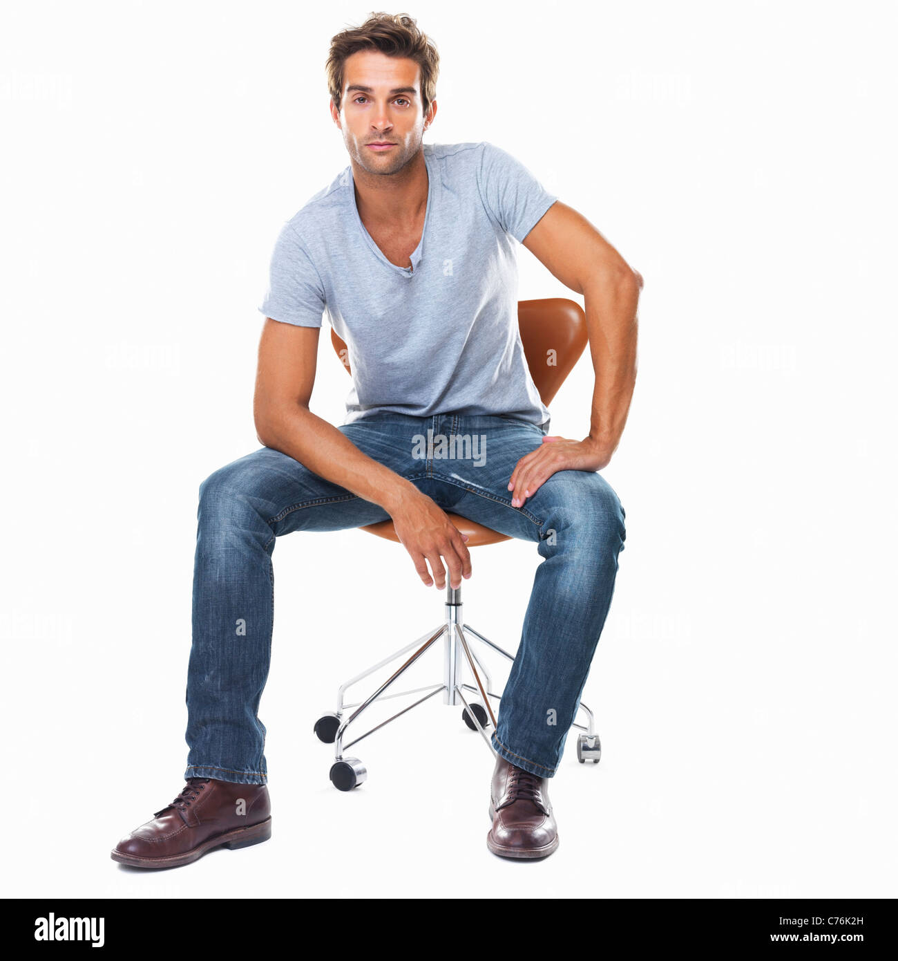 Studio shot of smart young man sitting on chair Stock Photo - Alamy