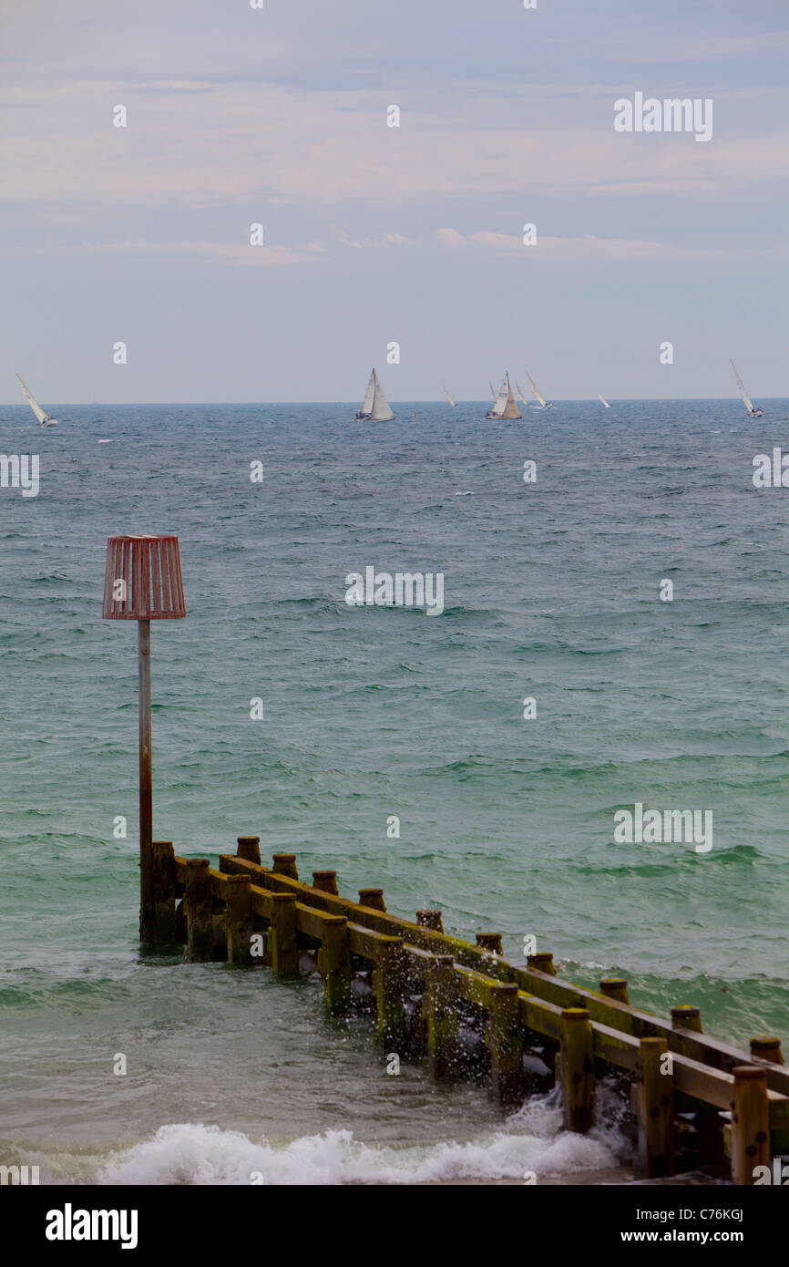 Timber groyne on Sussex coast on a pleasant day with sail boats on the ...