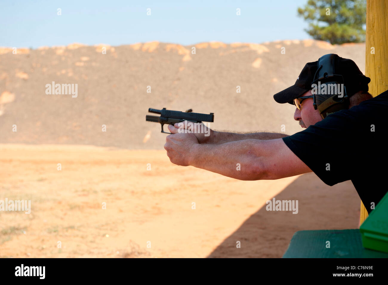 Senior Man Shooting a Semi-Automatic Firearm. Spent case is ejecting ...