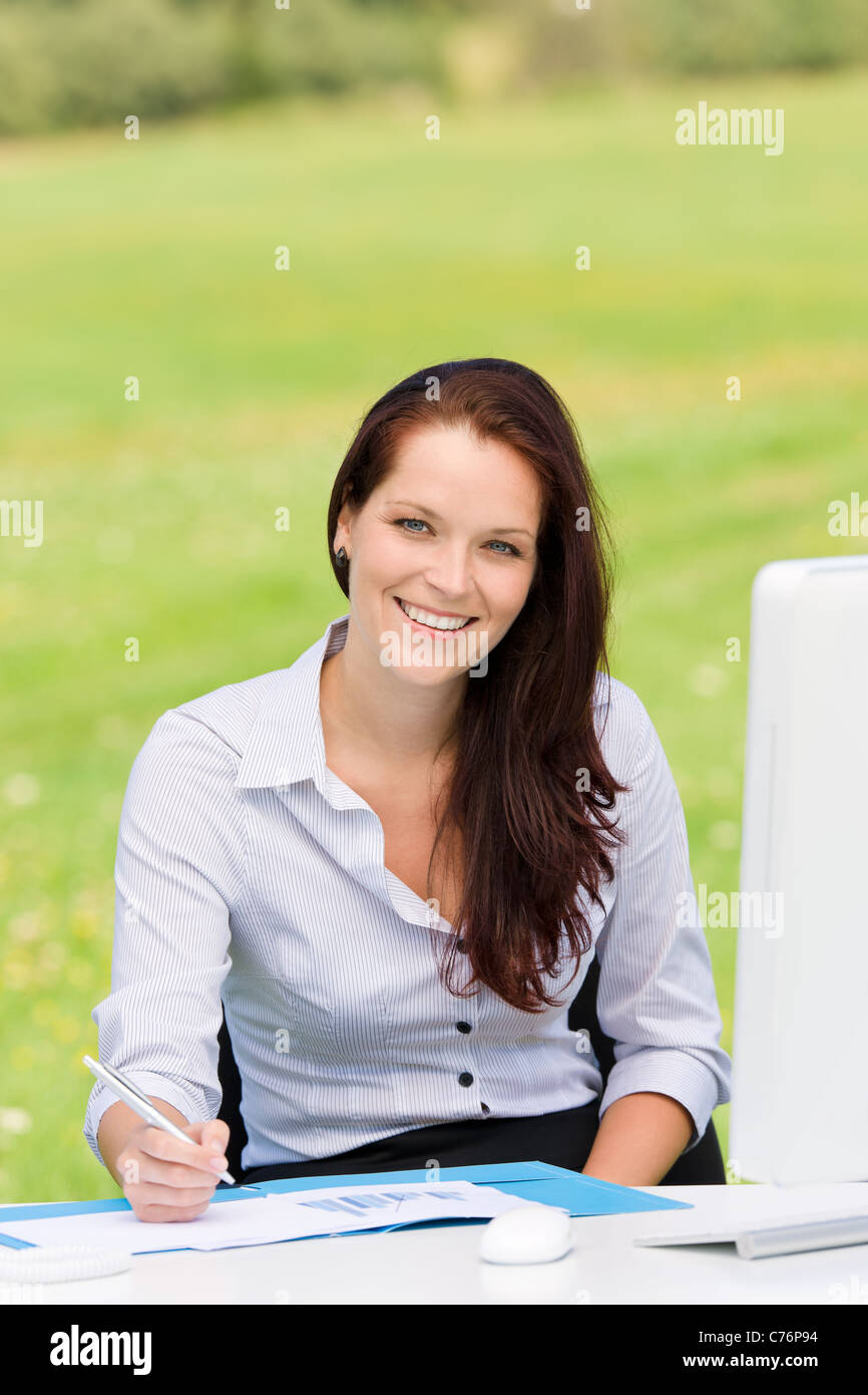 Young businesswoman in nature attractive smiling sitting behind ...