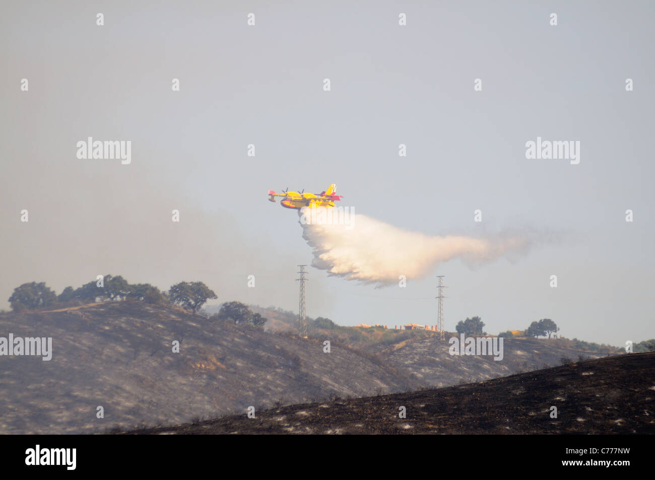 Fire bomber dropping water onto scrubland fire, Cabopino Golf, Costa ...