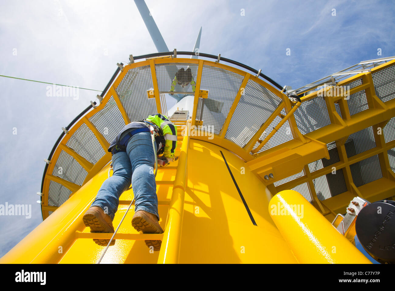 A worker climbs a wind turbine in the Walney offshore wind farm Stock ...