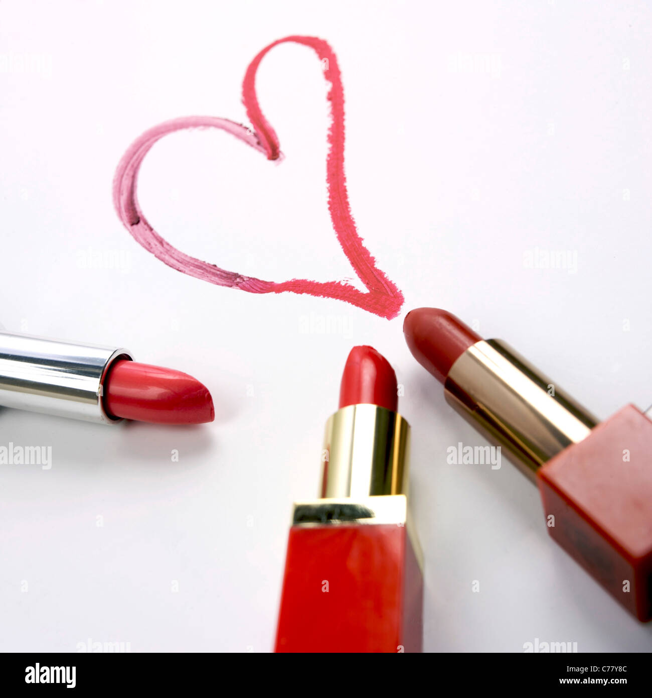 Red lipstick creating artistic heart designs on white paper Stock Photo ...