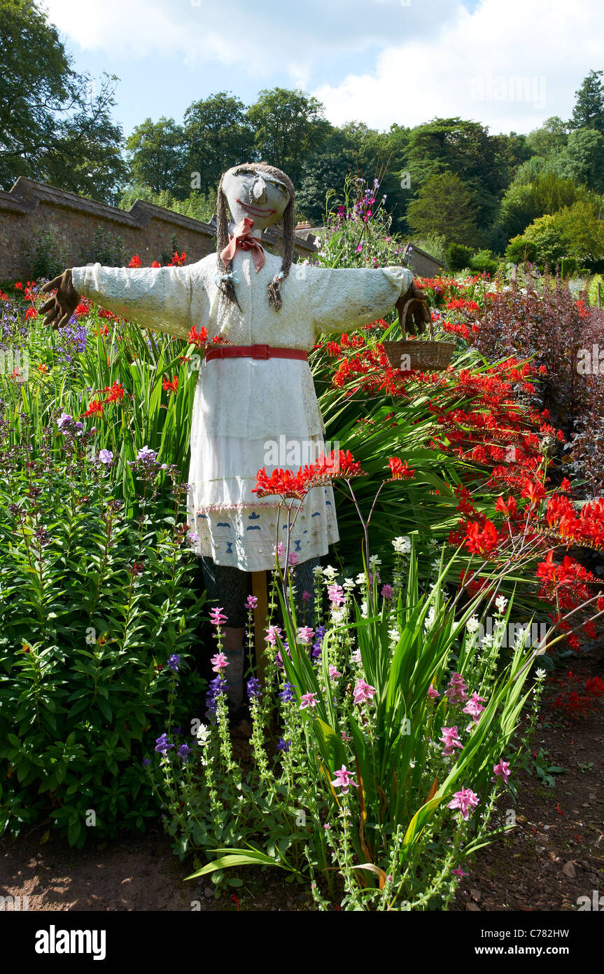 A large female scarecrow in flower beds in a walled garden in southern ...