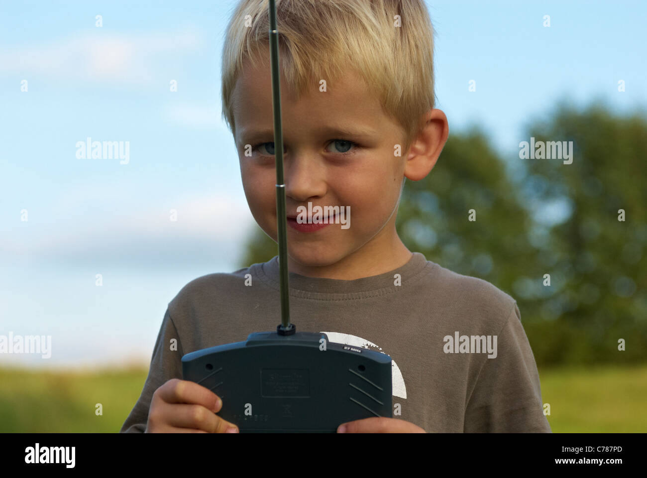 Portrait of young child blond boy flying a remote controlled model of ...