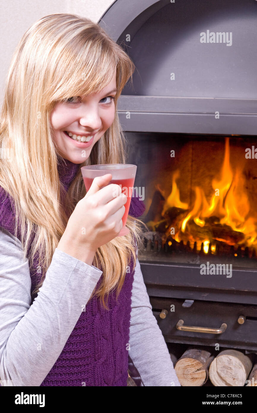 Smiling teen girl drinking tea near the fireplace Stock Photo - Alamy