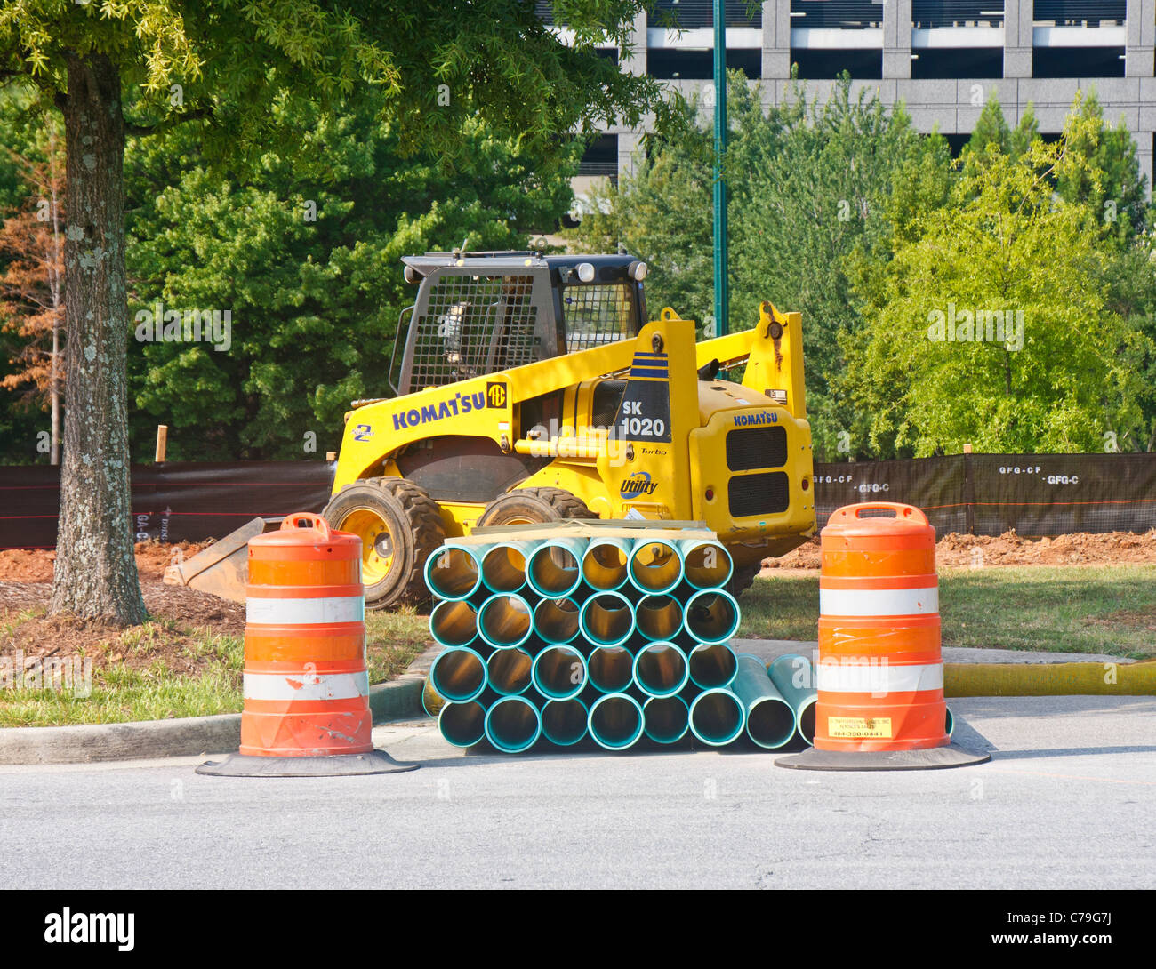 A yellow front end loader behind pipes and orange barrels Stock Photo ...