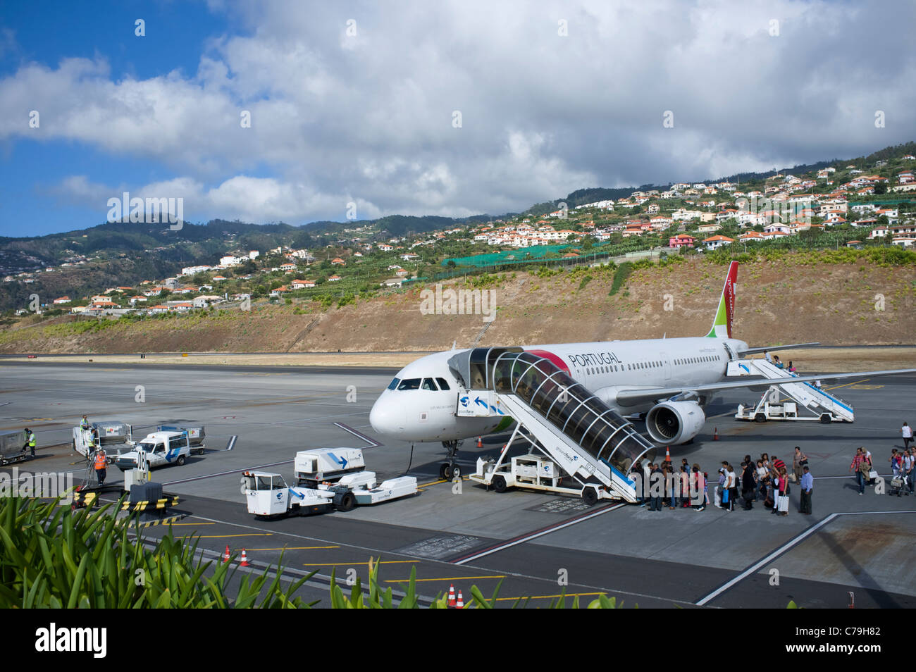 Madeira airport runway set in mountains by the sea. Passengers boarding ...