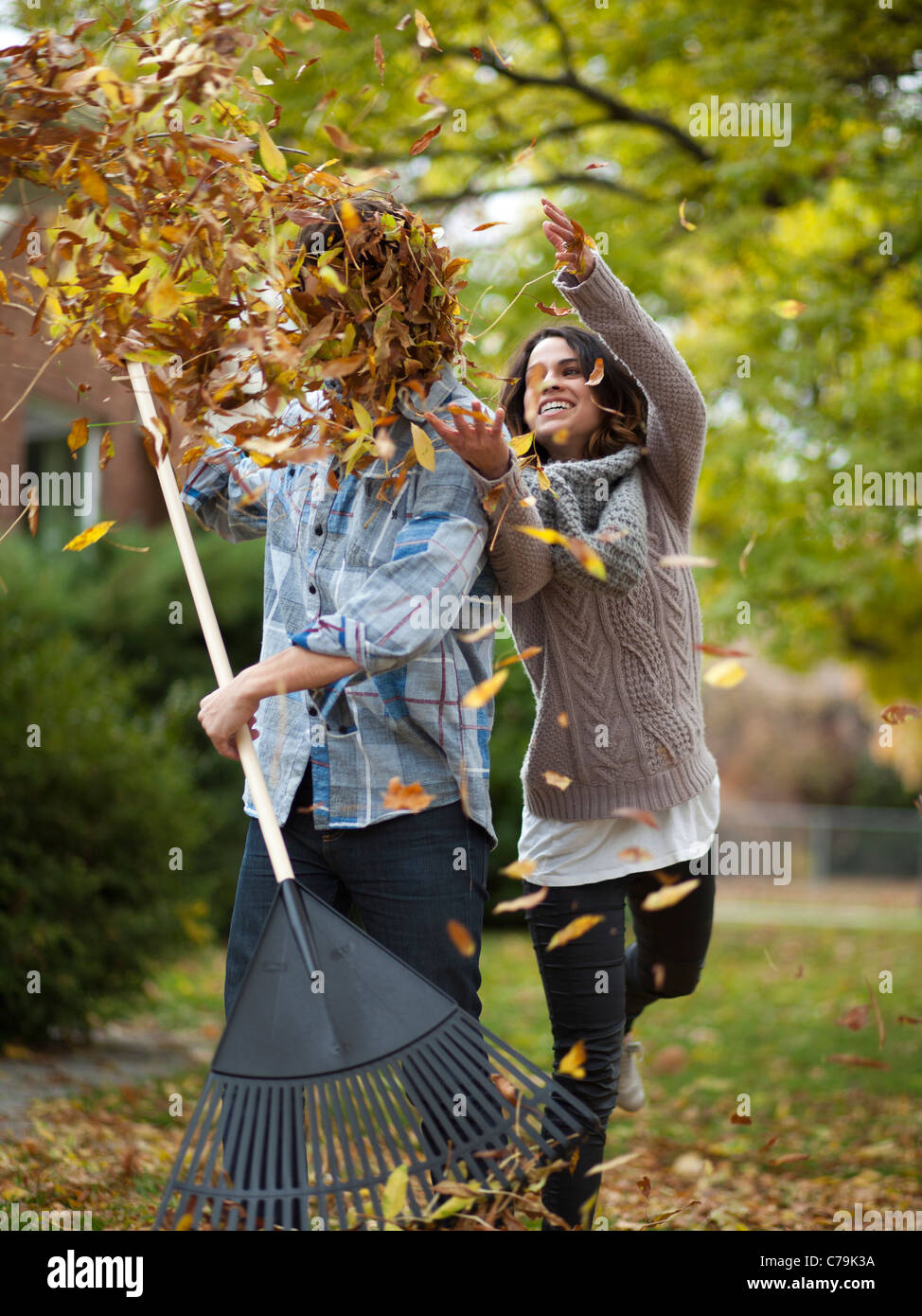 USA, Utah, Provo, Young woman throwing leaves over husband in garden ...