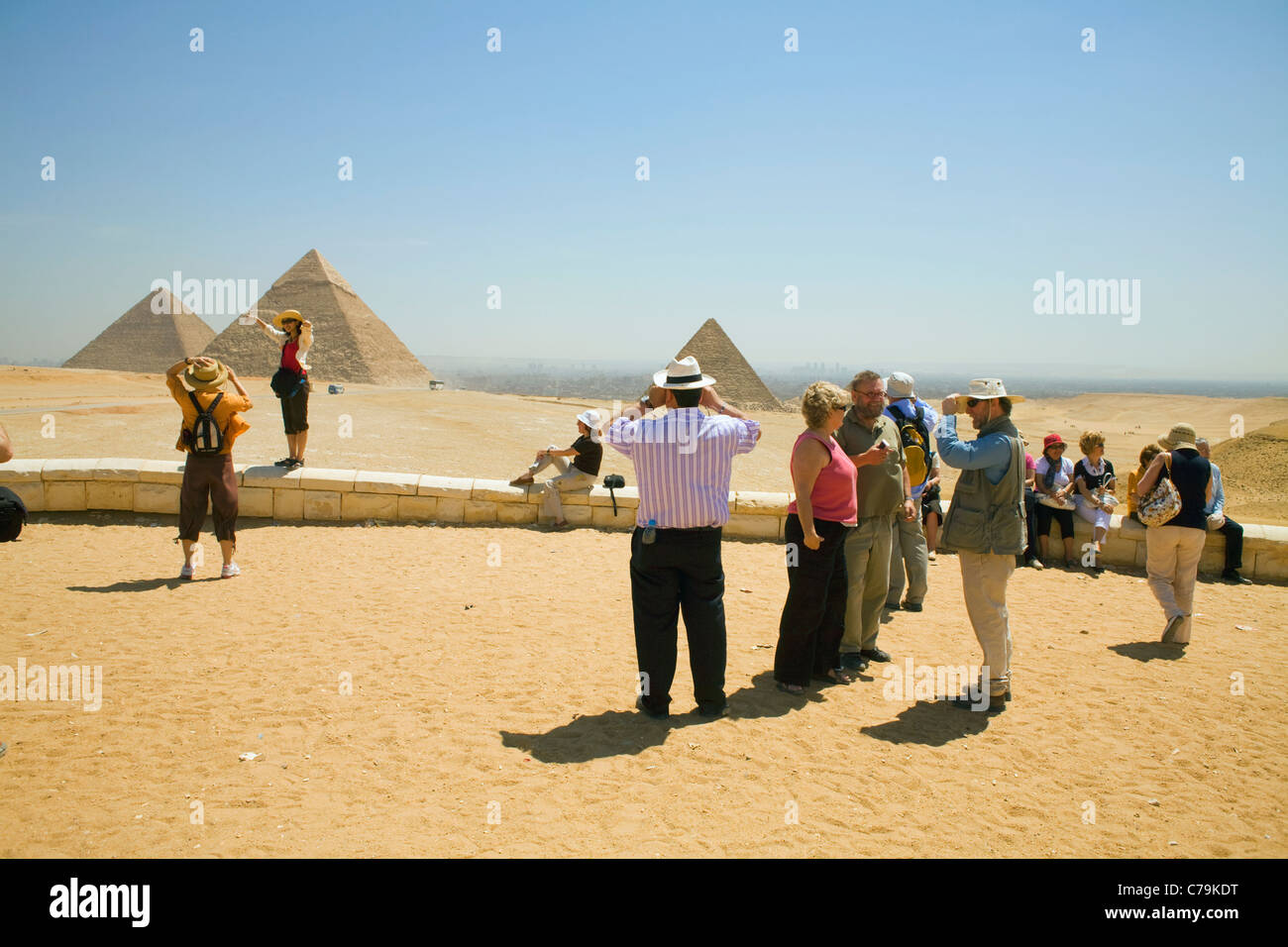 Tourists photograph one another with the Pyramids of the Giza Plateau ...
