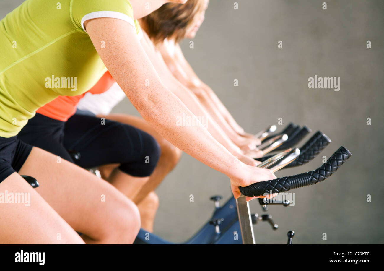 Three people working out on a stationary bicycle in the gym Stock Photo ...