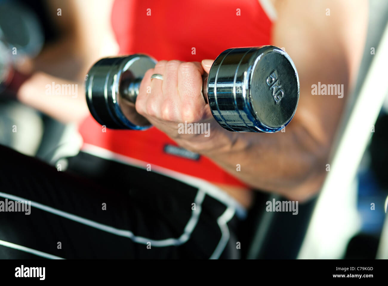 Woman lifting hand weights in a gym, focus on hand of woman and front ...