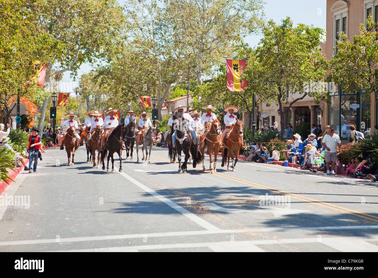 Hispanic horseback riders trot up the street in the opening day parade ...