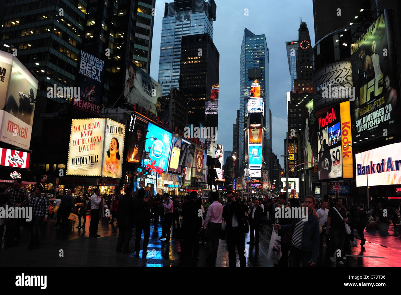 Evening twilight view people, wet ground reflections, neon signs ...