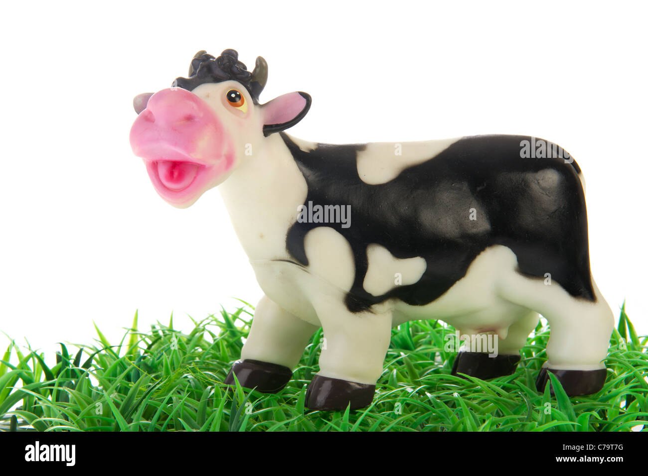 Toy cow in the green grass on white background Stock Photo - Alamy