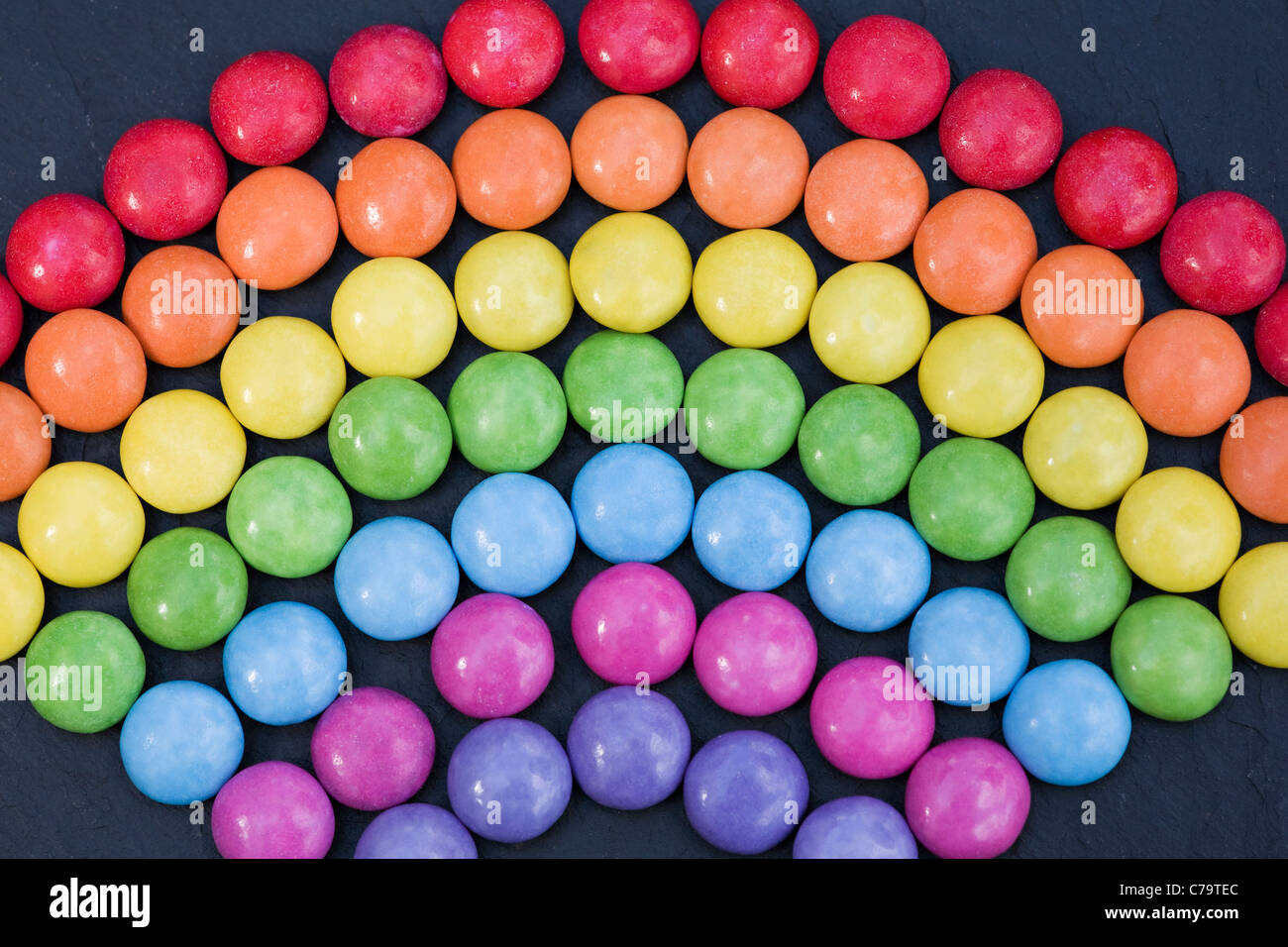 Rainbow smartie pattern on black background. Close up Stock Photo - Alamy
