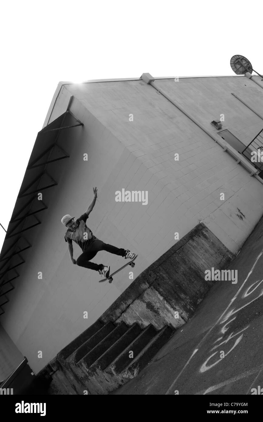 A young skateboarder launches off a concrete loading dock in an urban ...