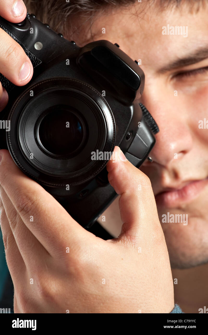 A young teenage photographer taking a photo with his DSLR camera ...