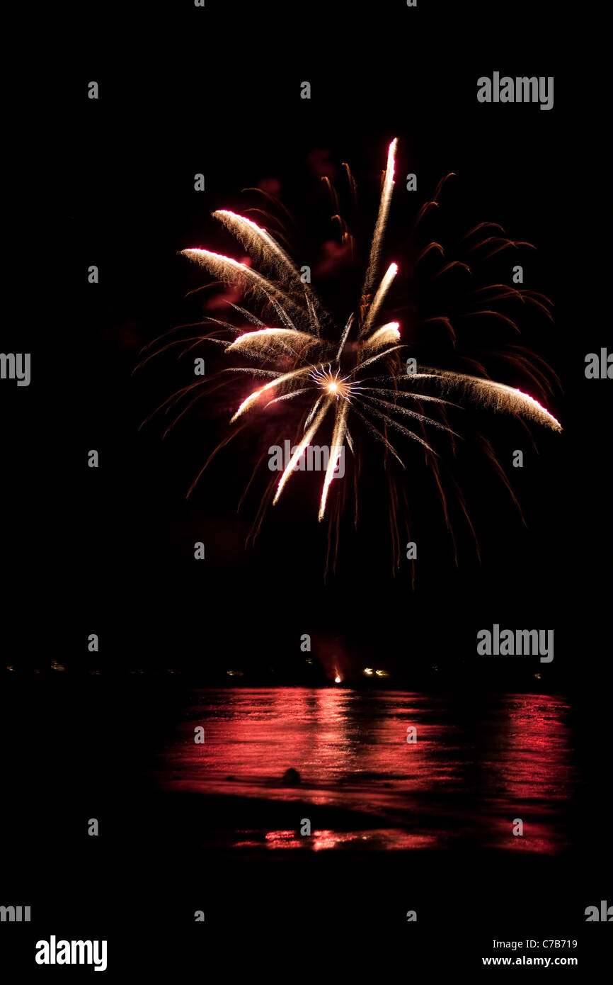 Beautiful fireworks going off over the dark night sky reflecting over ...