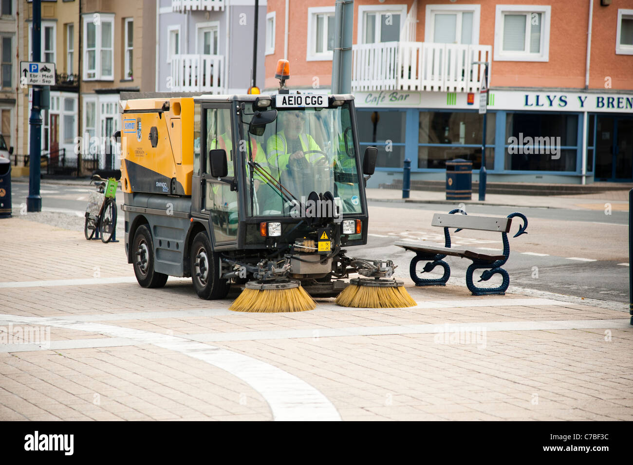 a small compact Schmidt Swingo 200 roadsweeper cleaning the pavement on ...
