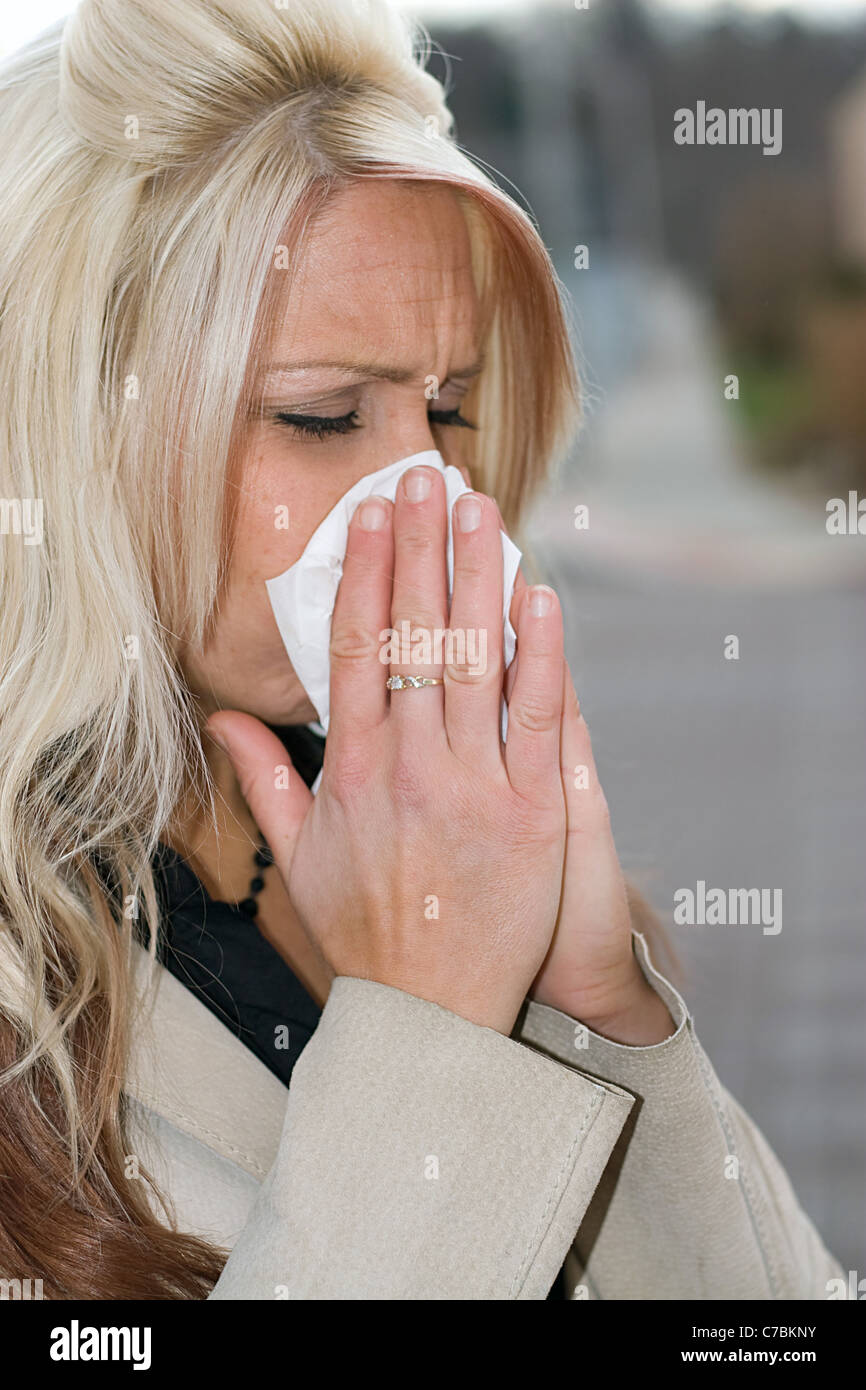 This young woman sneezing into a tissue either has a cold or really bad ...