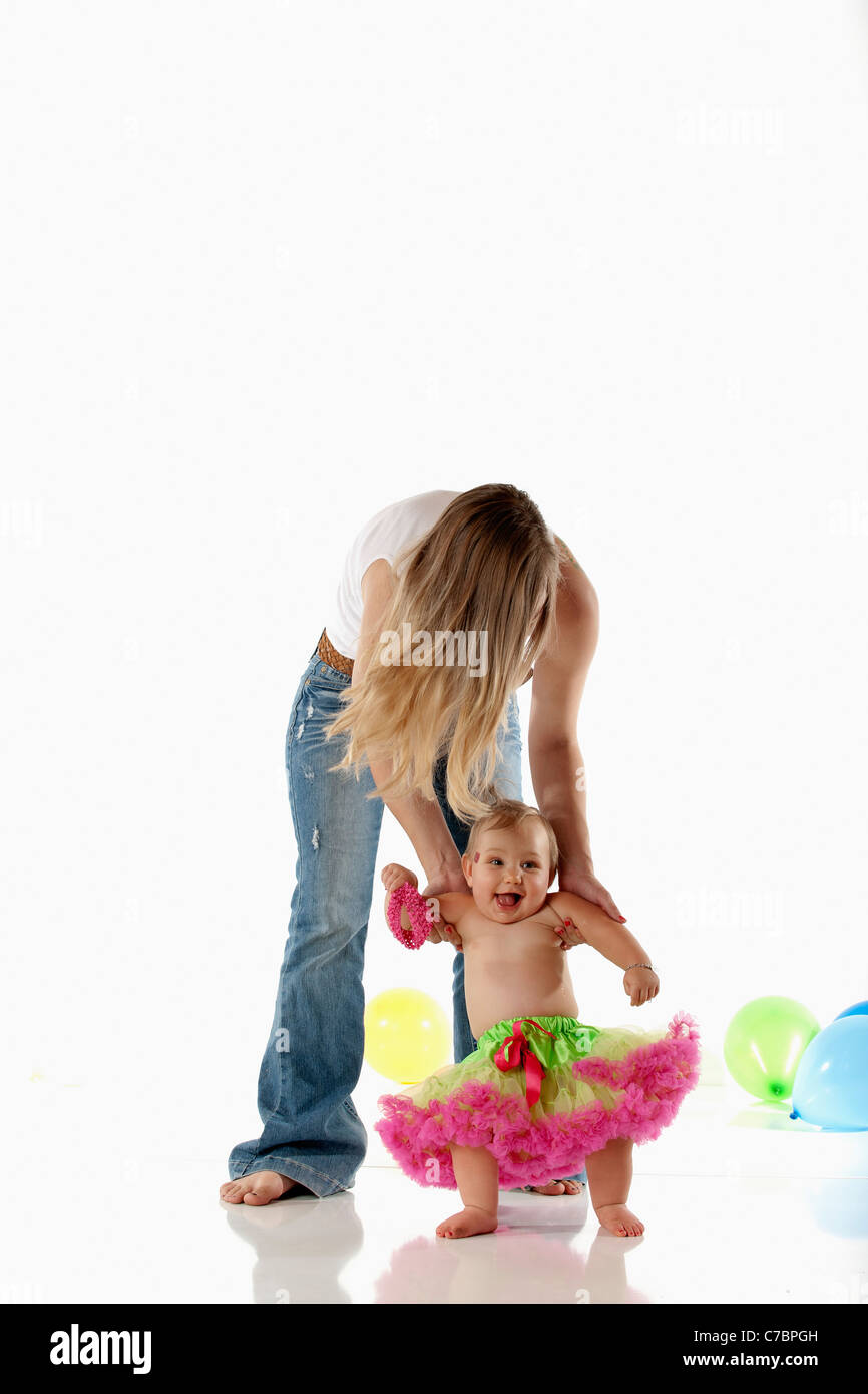 Young mother helping baby girl stand on her own Stock Photo - Alamy