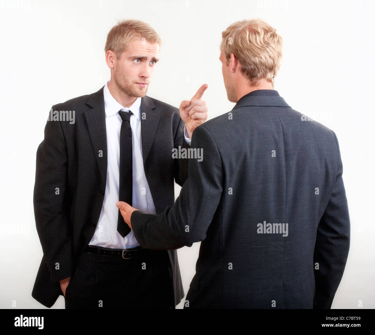 two young businessmen standing, discussing, arguing - isolated on light ...