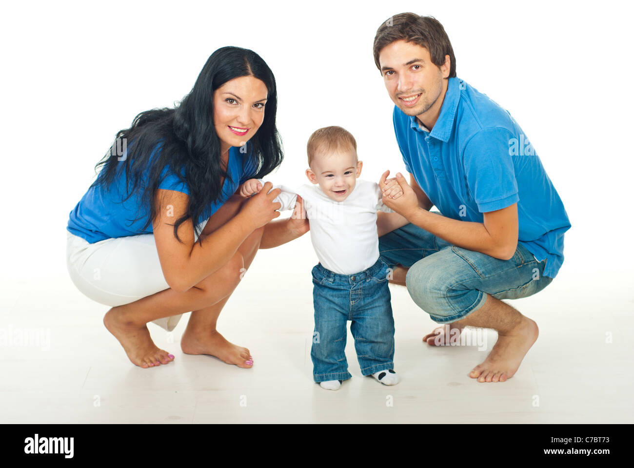 Parents helping their baby to make first steps and smiling together ...