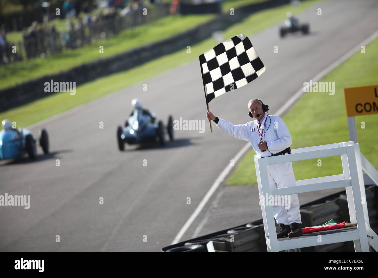 Cars speed past the checkered flag at the Goodwood Revival Meeting 2011 ...