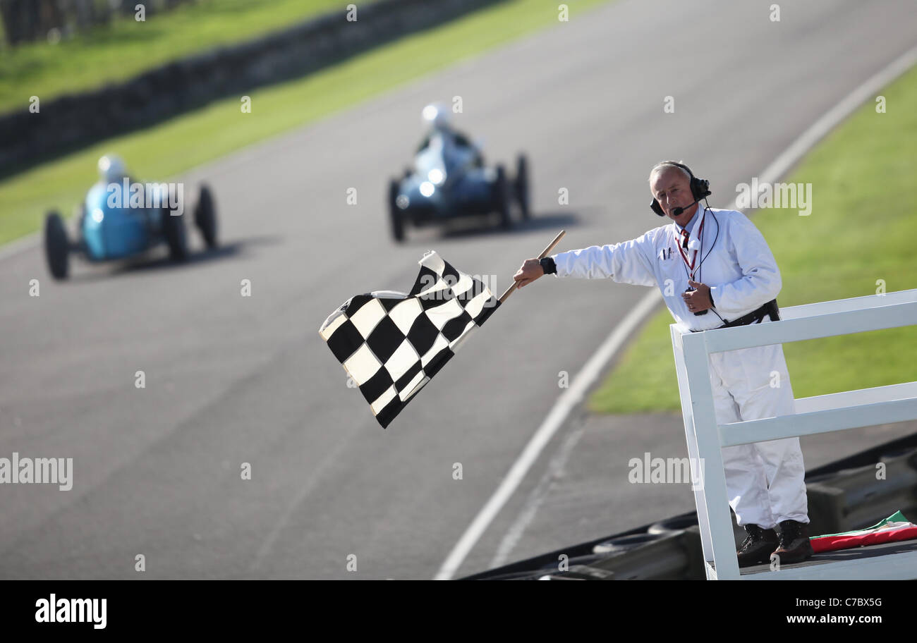 Cars speed past the checkered flag at the Goodwood Revival Meeting 2011 ...