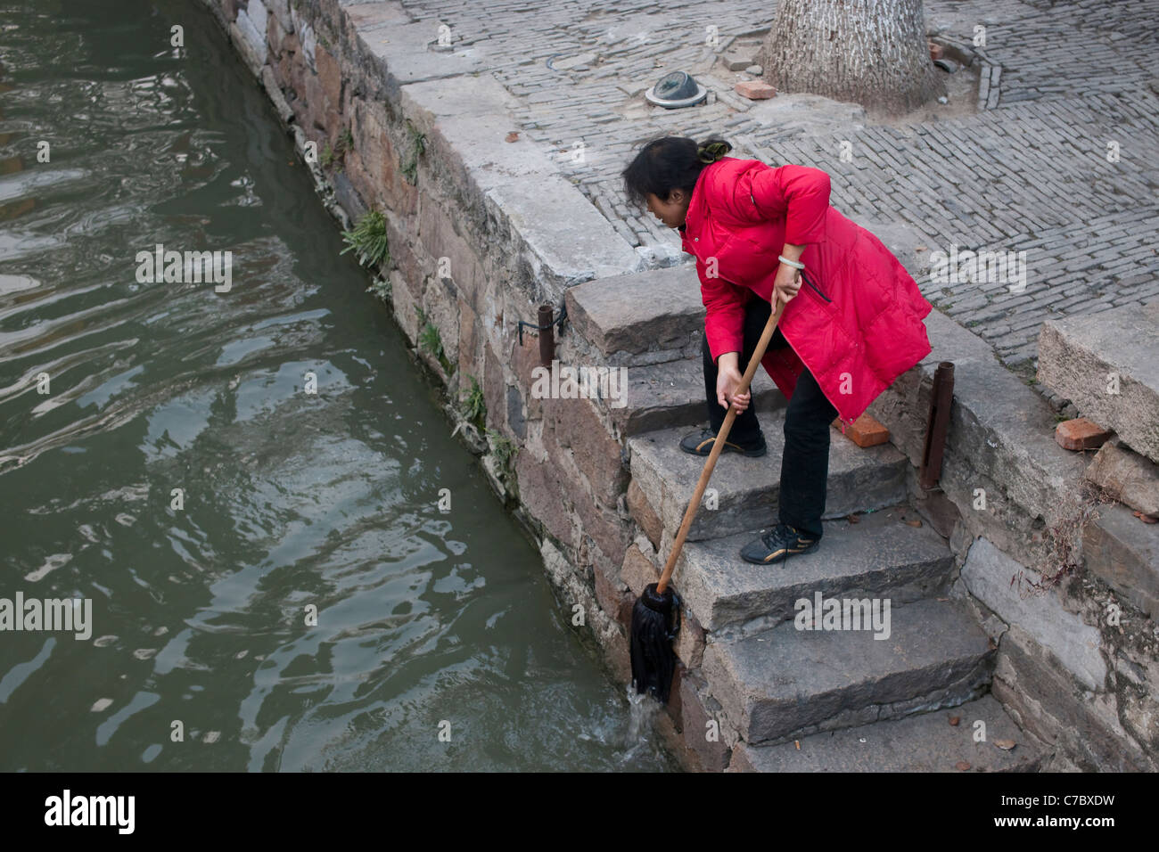 Woman rinsing out a mop in the canal at Tongli water village Stock ...