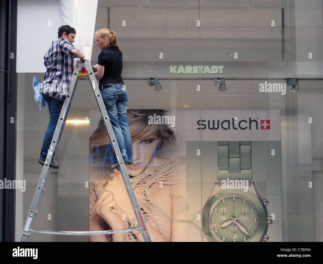 Women attaching a sign in a Swatch store in Leipzig Saxony East Germany ...