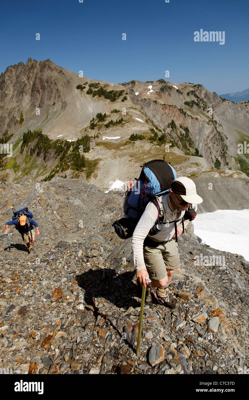 Backpackers scrambling up rock ridge, Bailey Range Traverse, Olympic ...