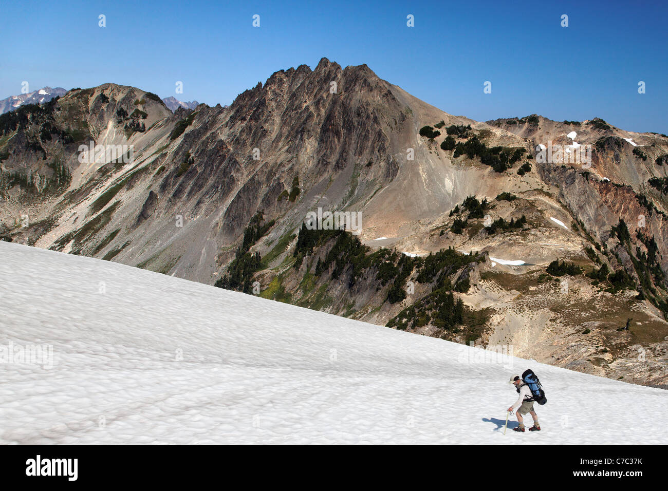 Backpacker climbing snow slope below Pulitzer Peak, Bailey Range ...