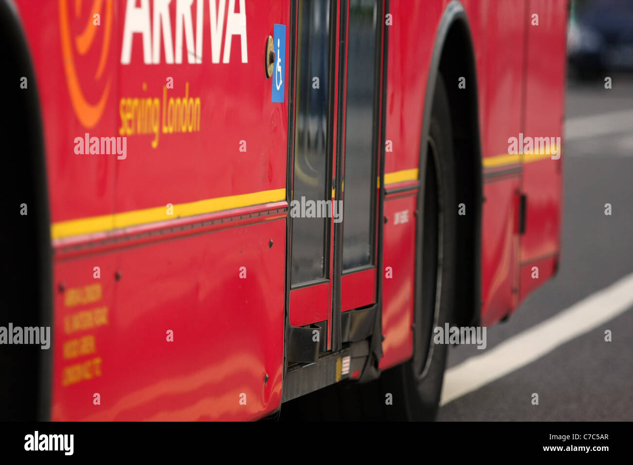 The lower part of a side of a London bus as it travels along a road ...