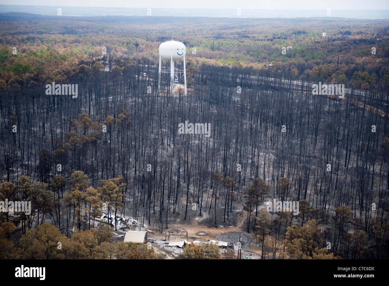 Water tower with smiley face painted on it stand above wildfire damage ...