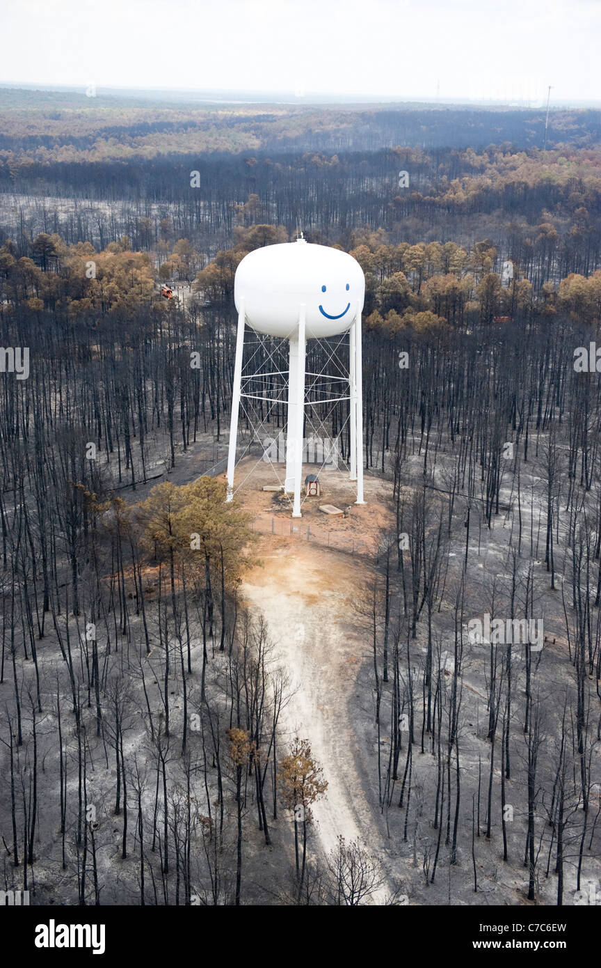 Water tower with smiley face painted on it stand above wildfire damage ...