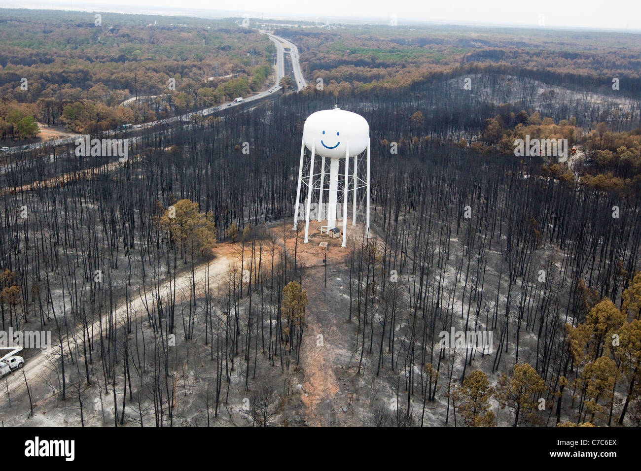 Water tower with smiley face painted on it stand above wildfire damage ...