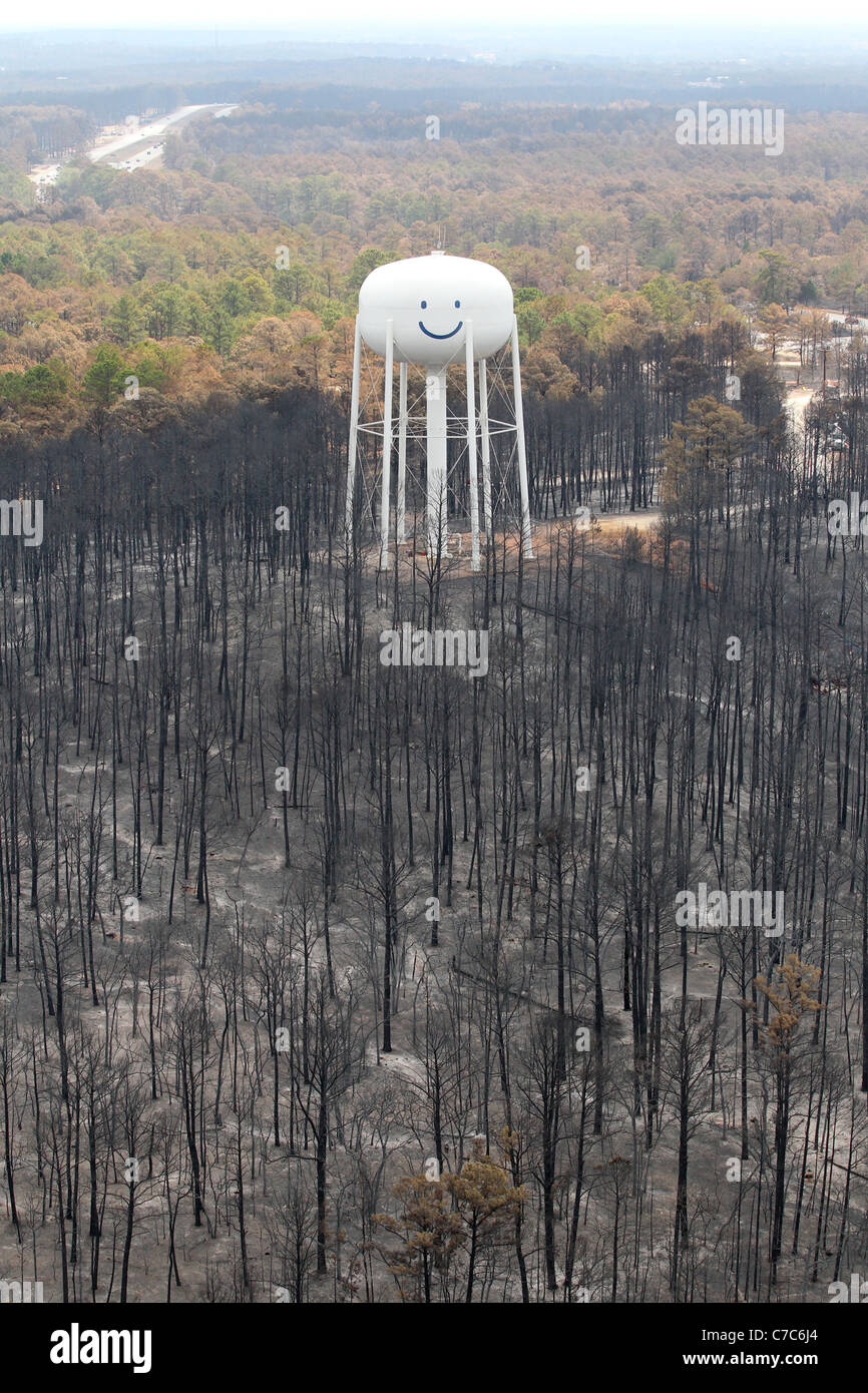 Trees burned by wildfire surround a water tower with a "happy face" on ...