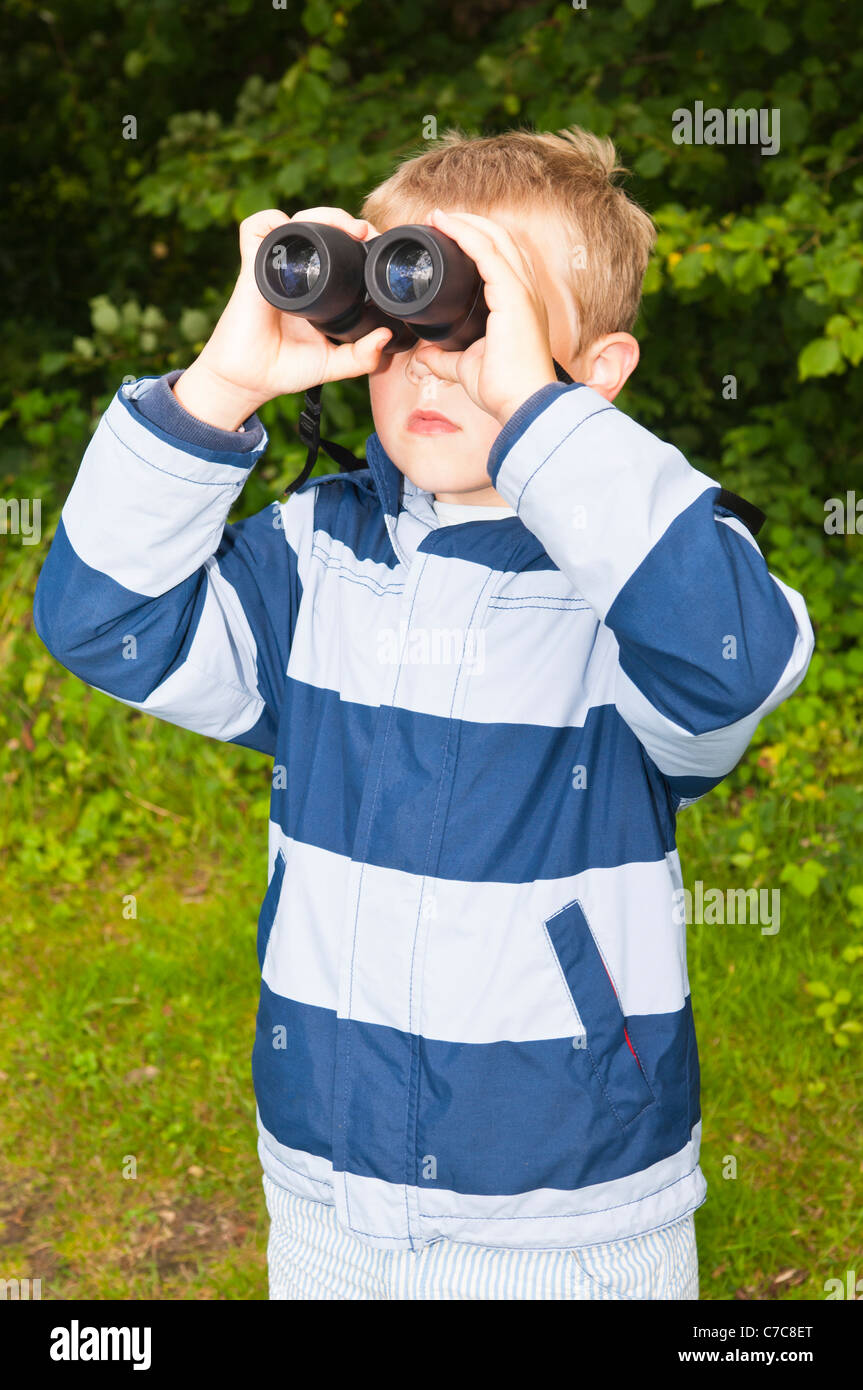 A seven year old boy birdwatching with binoculars at Fairhaven woodland ...